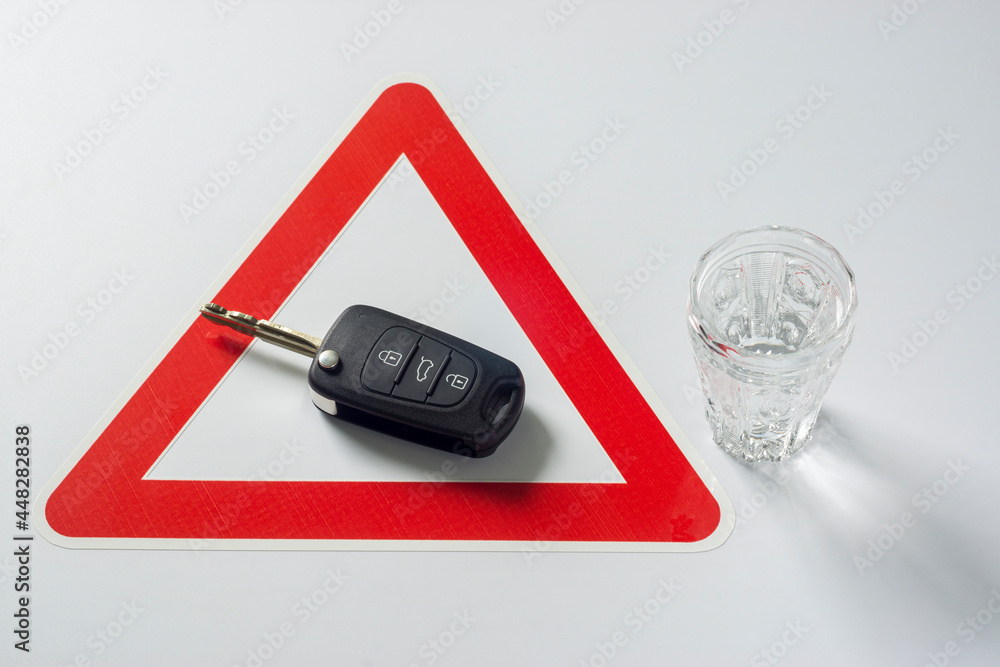 Auto key and shot of vodka in red prohibiting frame of road signs on ...