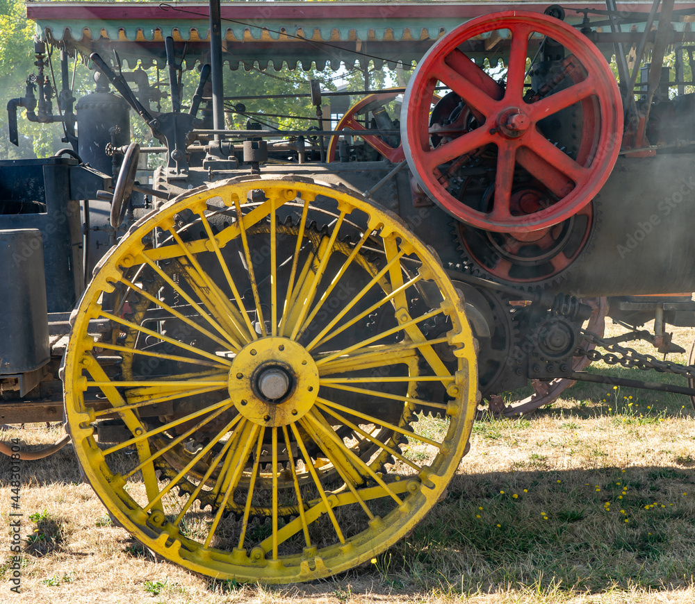 The iron spoked rear wheels and fly wheel of a vintage steam powered ...