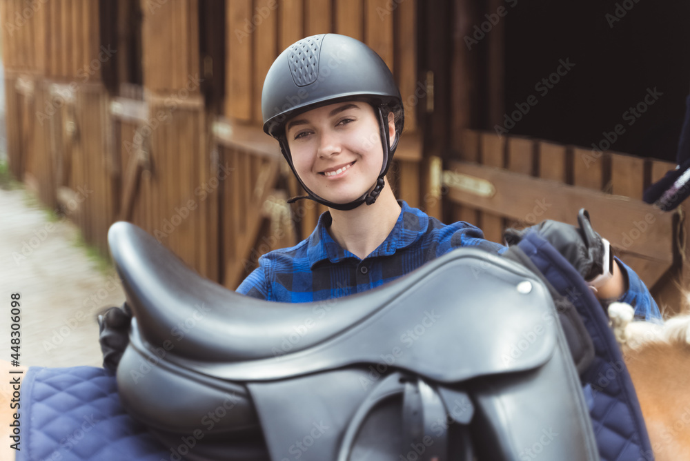 Female jockey standing with her horse outside the horse stable. The ...