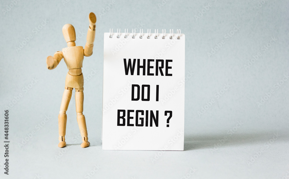 where do I begin question written on notepad with wooden doll on blue ...