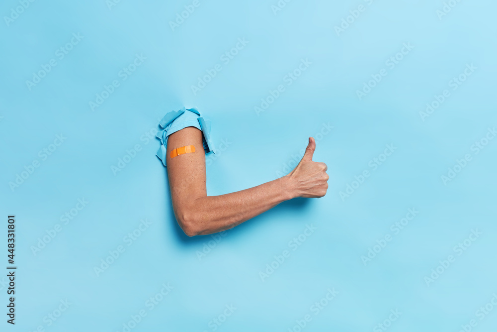 Horizontal shot of unknown person breaks arm through paper blue ...