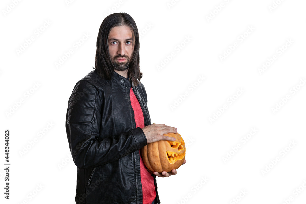 A man with a beard and long hair in a black jacket with a pumpkin in ...