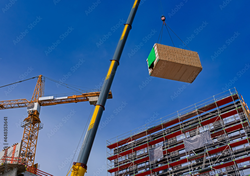 Crane lifting a wooden building module to its position in the structure ...