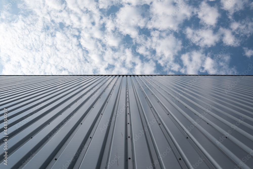 View upwards to the facade of a warehouse with a cladding of silver ...
