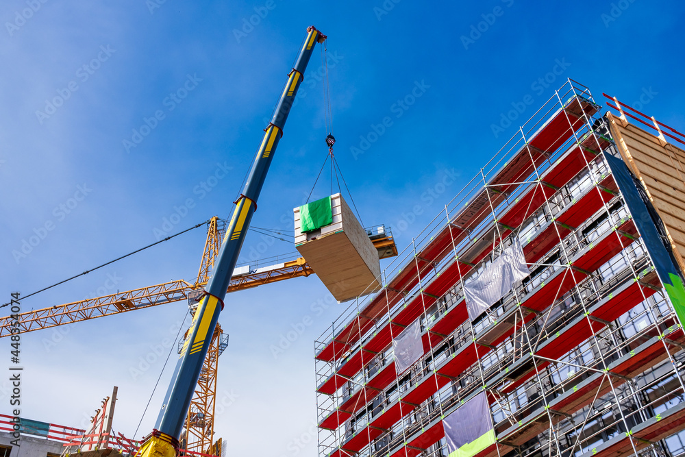 Crane lifting a wooden building module to its position in the structure ...