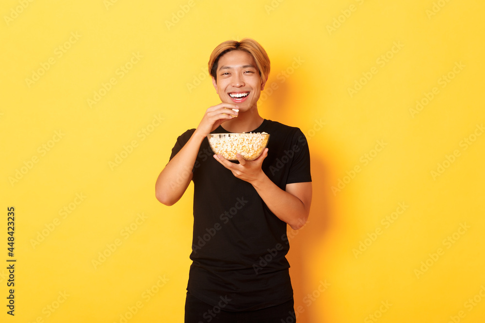 Carefree happy asian guy with blond hair, watching comedy, laughing and ...
