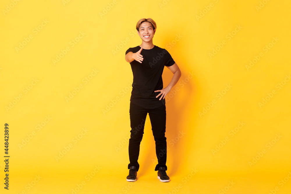 Full-length of friendly handsome korean guy with blond hair, extending ...