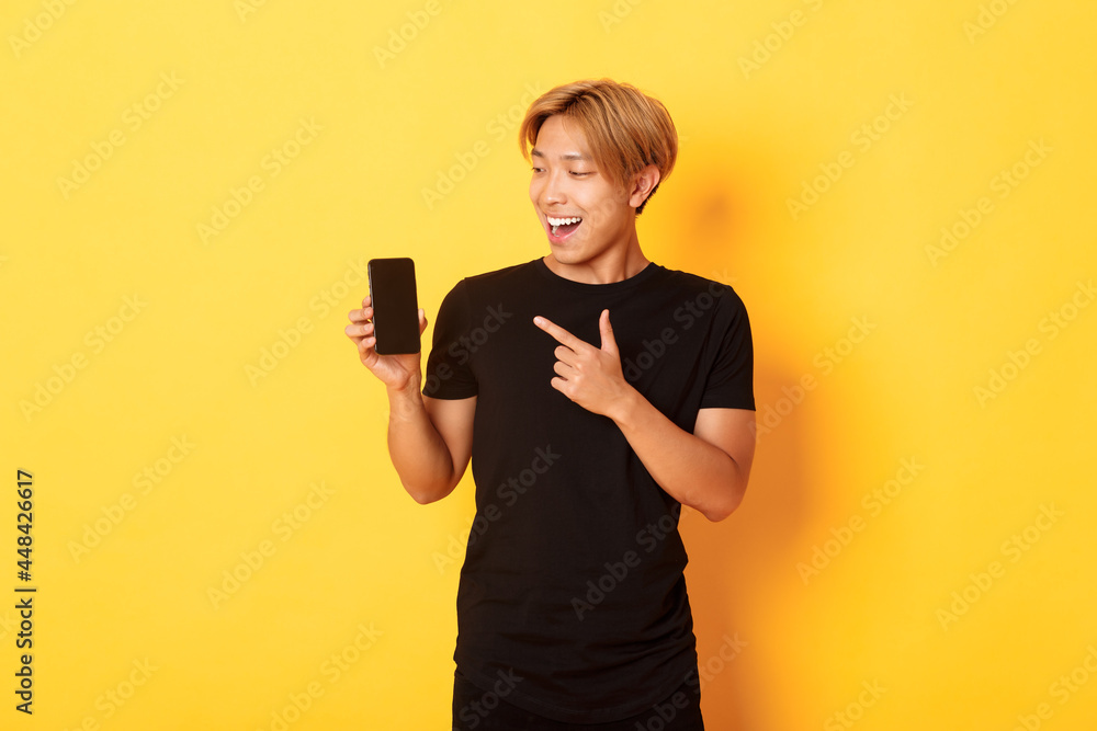 Portrait of satisfied asian guy pointing finger and looking at ...