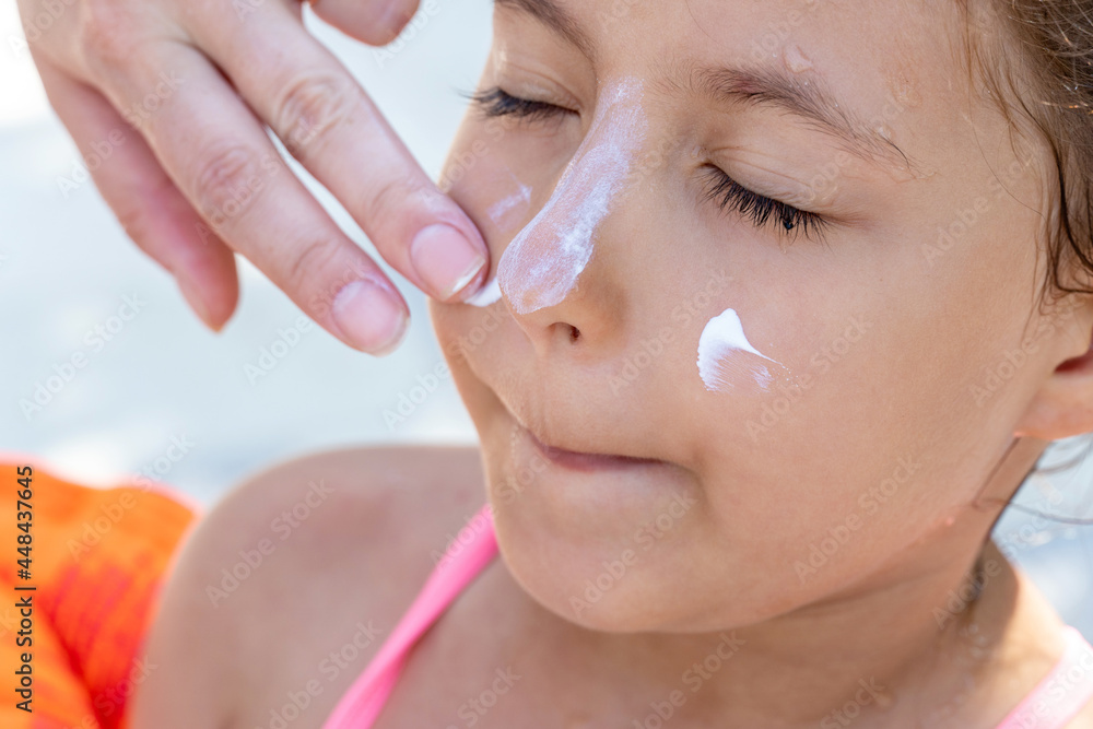 Applying sunscreen cream to the face of a small child, sun and ...