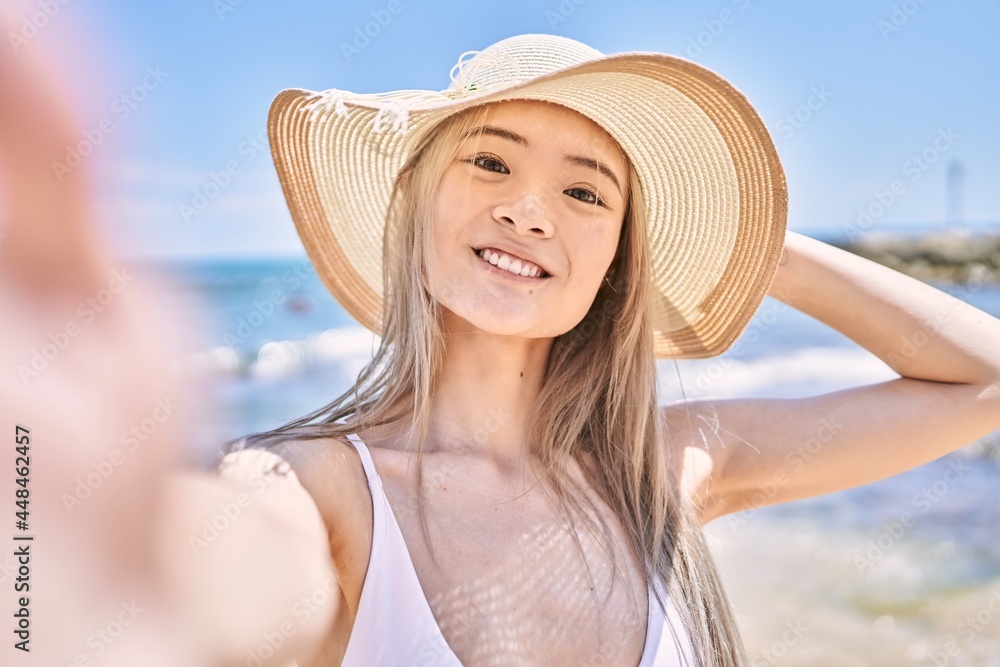 Young chinese girl wearing bikini making selfie by the camera at the beach. Stock Photo | Adobe ...