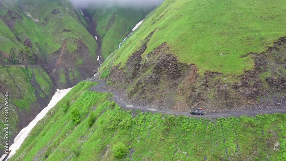 Cinematic drone shot of a vehicle driving on the Road to Tusheti, one ...