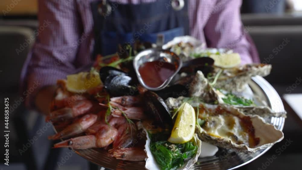 Waiters carries mixed seafood set, lobster shrimp, king prawns, mussels ...