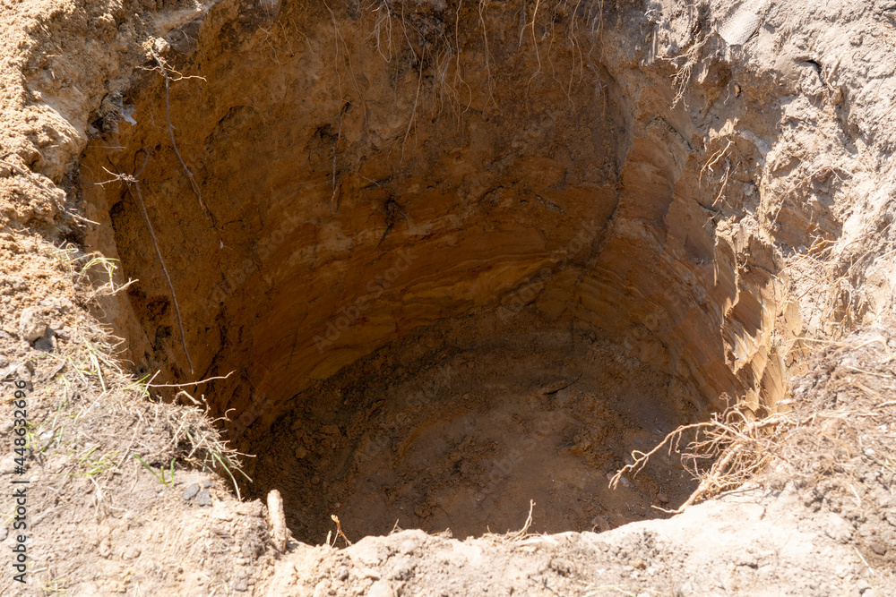 a deep hole is dug in the ground, a sinkhole in the ground Stock Photo ...