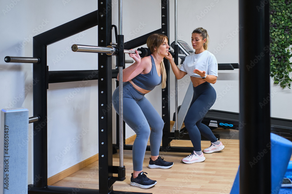 Young woman lifts barbell in a gym with the help of a trainer Stock ...