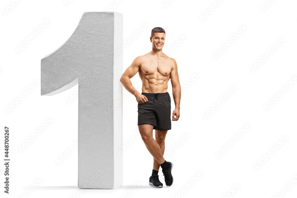 Full length portrait of a shirtless bodybuilder leaning on number one ...