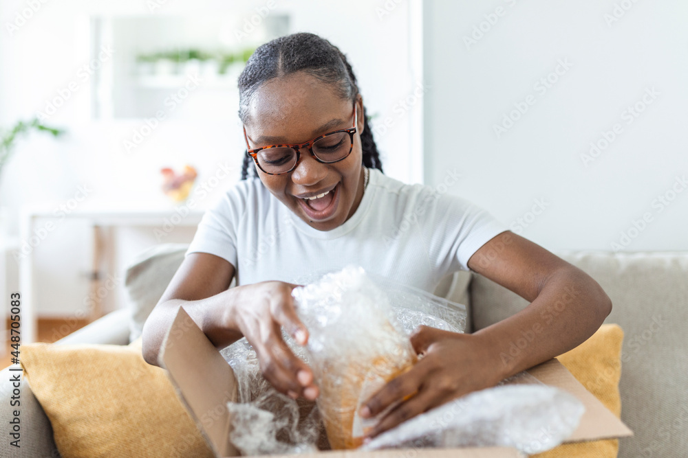 Smiling african American millennial girl sit on sofa at home open ...