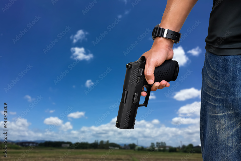 Male holds automatic 9mm black pistol, blurred background, concept for ...