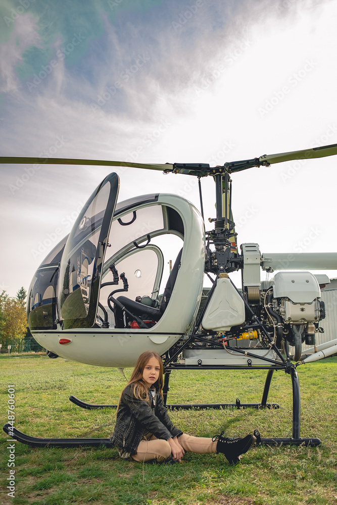 Tween girl sitting on green grass of flying field near helicopter Stock ...