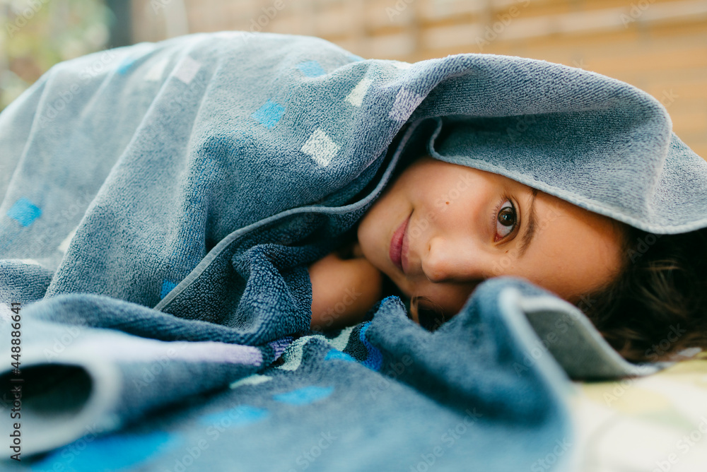 Kid wrapped in blue towel hunched and looking at camera Stock Photo ...