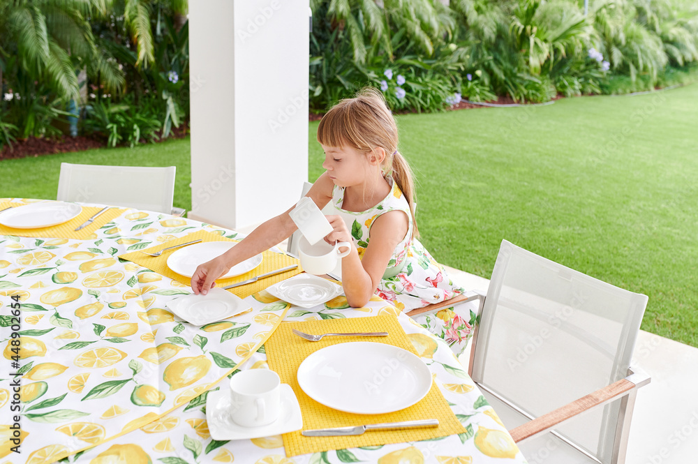Foto de Little girl setting a patio table for lunch do Stock | Adobe Stock