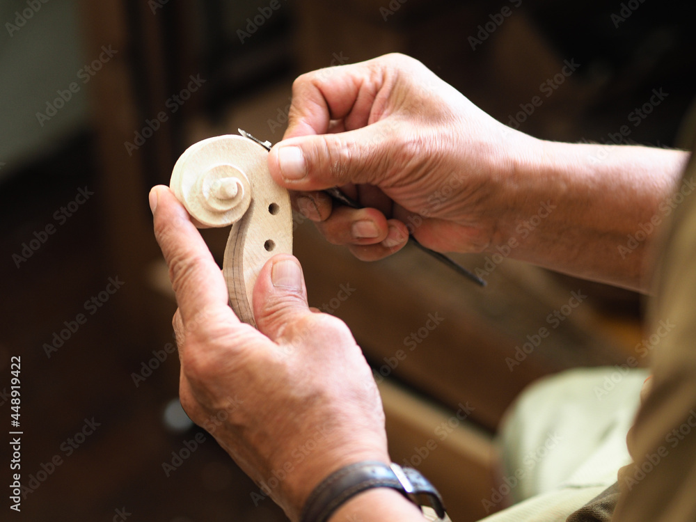 Luthier carving a classic violin head and curl with a small knife in ...