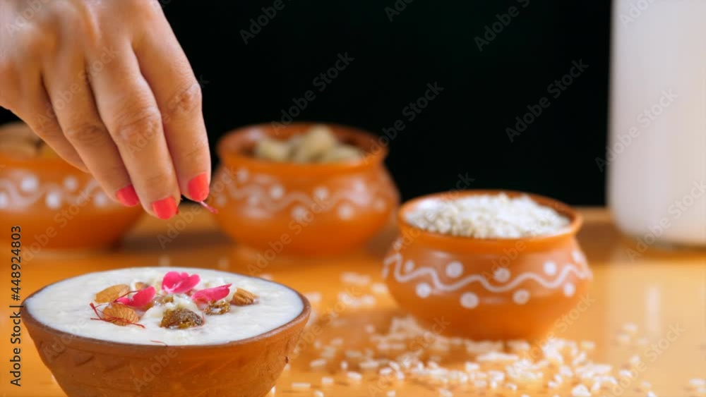 Female hand adding saffron / Kesar to a bowl of delicious rice pudding ...
