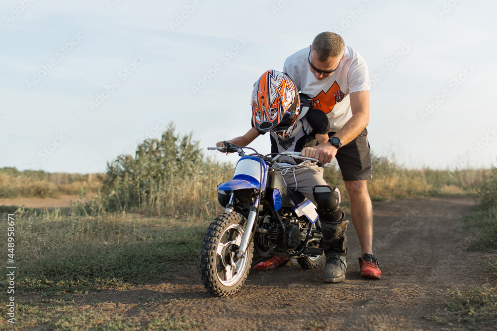 Kid on a motorcycle doing motocross. A little boy learns to ride a ...