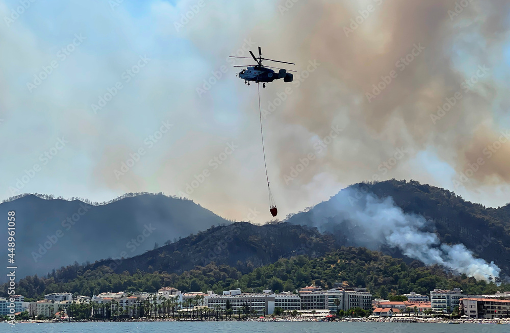 fire fighting helicopter with bucket of water sea during forest fires ...