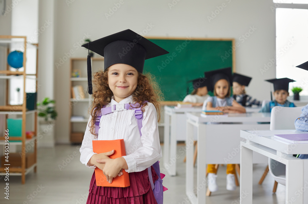 Portrait of a beautiful little curly elementary school graduate girl ...