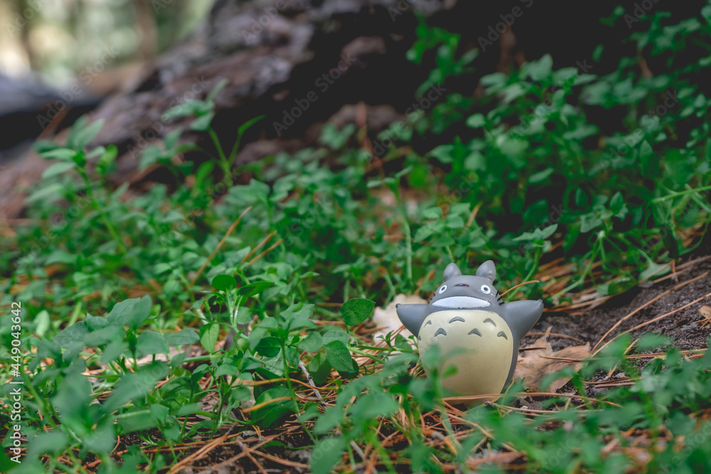 Little "Totoro" figure between grass and leaves in the ground of the ...