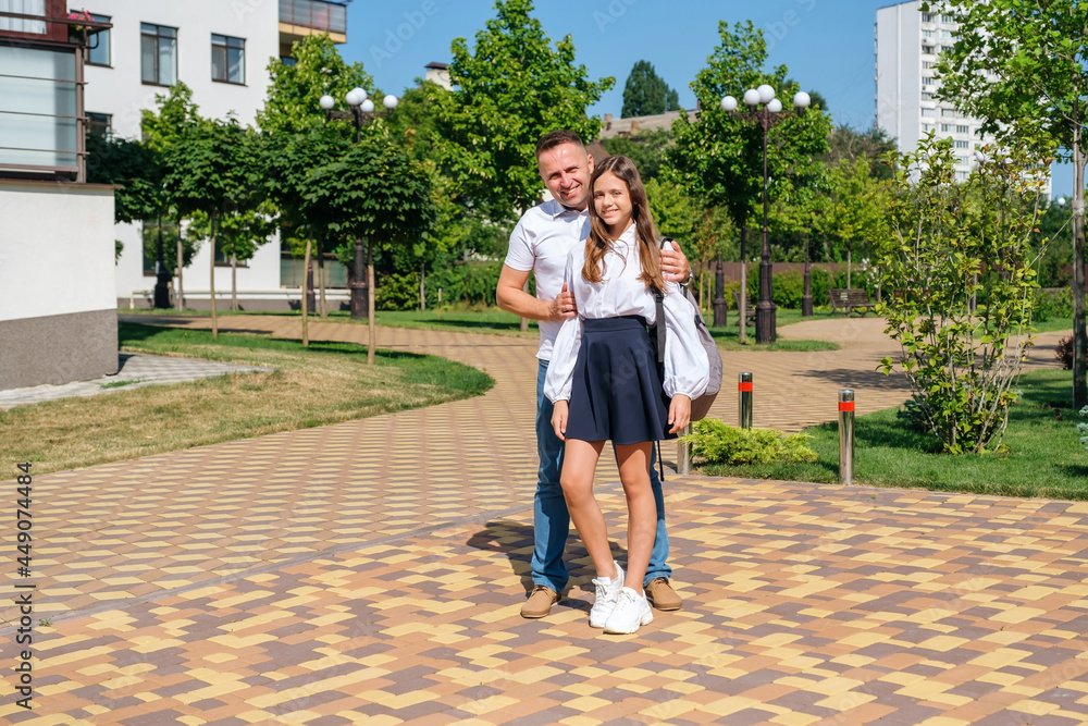 Back to school. Smiling father proudly hugs his schoolgirl daughter ...