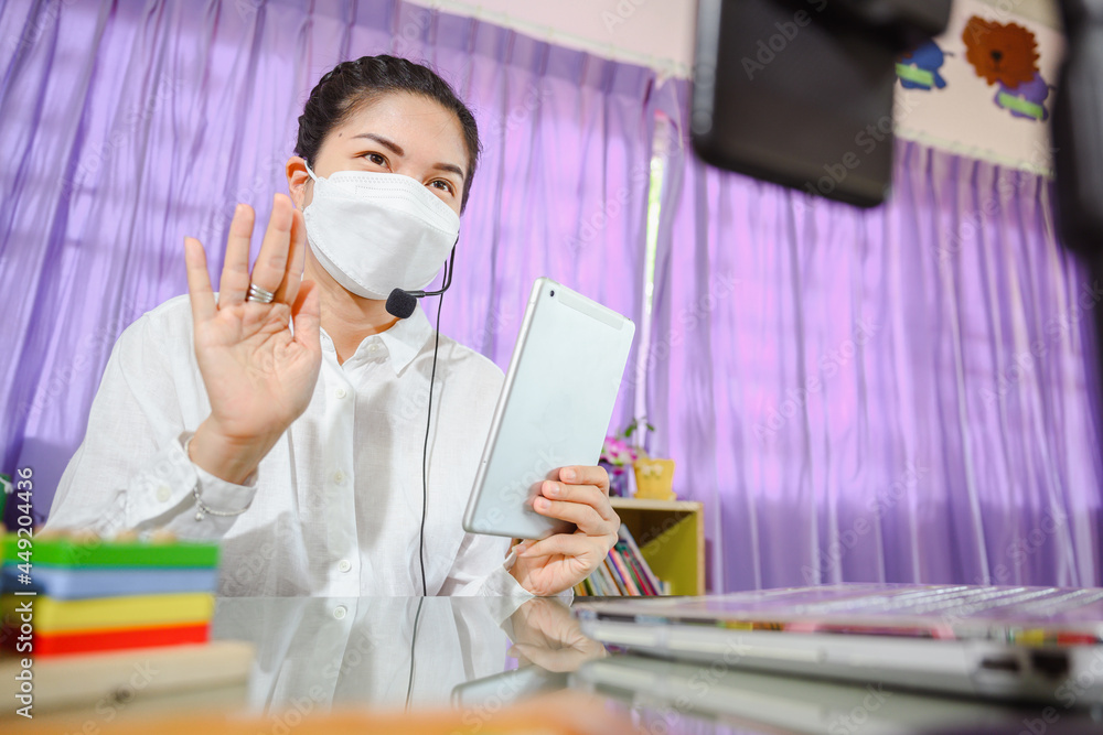 Asian female teacher wearing a mask is teaching students to study ...