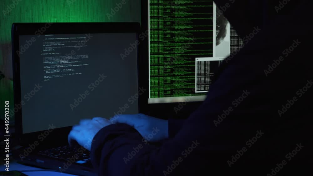 A hacker in a dark room. Hacking the system. The code changes quickly ...