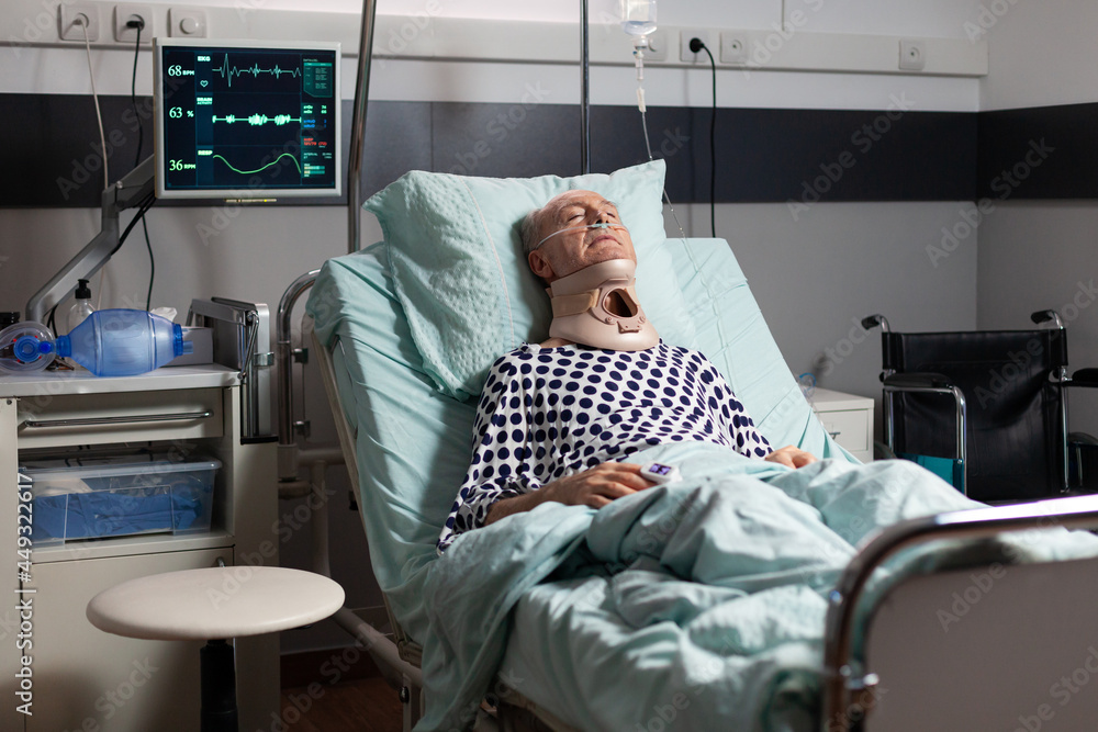 Elderly man laying in hospital room bed wearing cerival collar, with iv ...