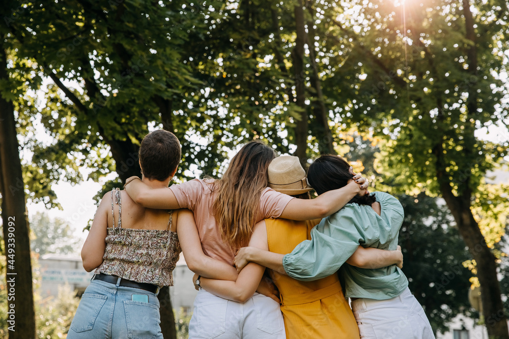 Group of four women in a park, hugging together from behind. Stock ...