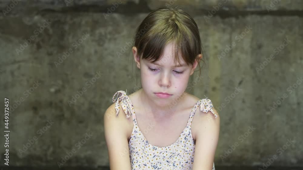 Emotional face of a charming girl. Little sad child sits on the ...