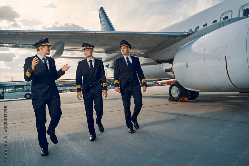 Three elegant aviators going along the runway Stock Photo | Adobe Stock