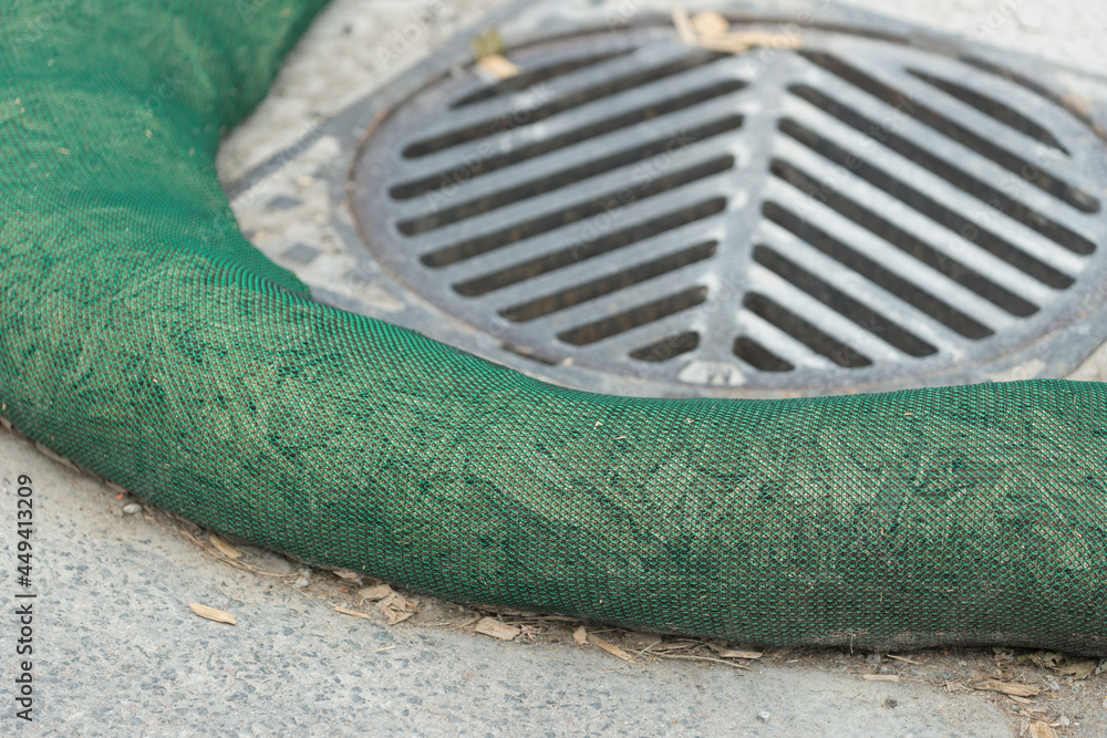 iron storm sewer cover and silt sock Stock Photo | Adobe Stock
