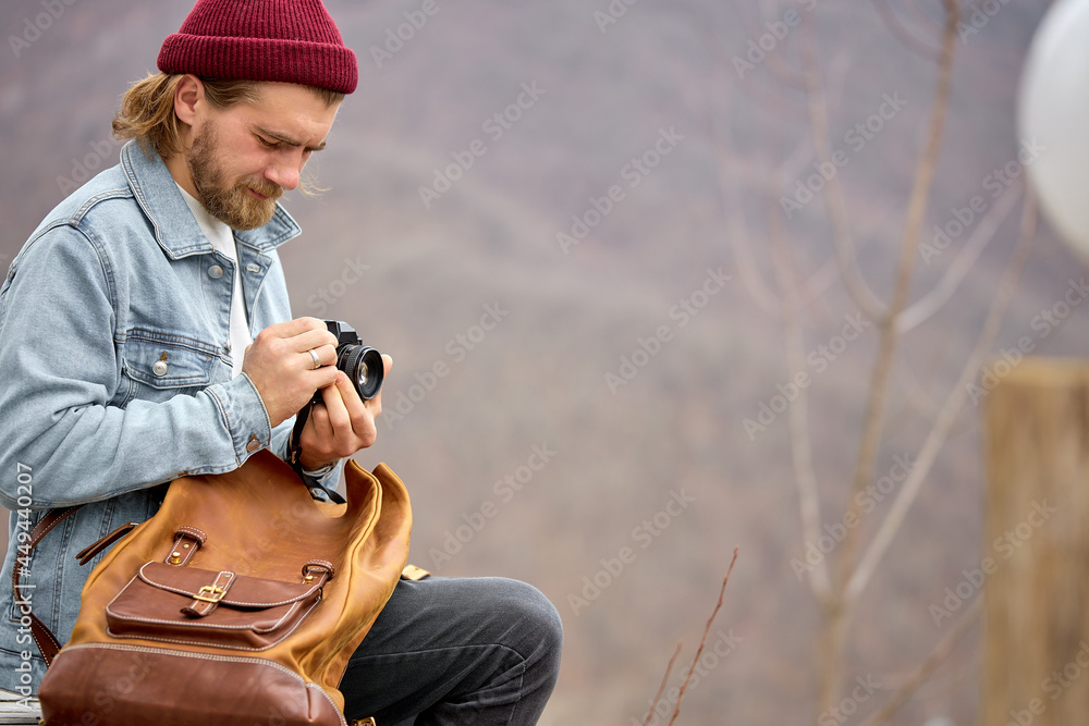 handsome guy sets up camera to take photo, in nature durng travel alone ...
