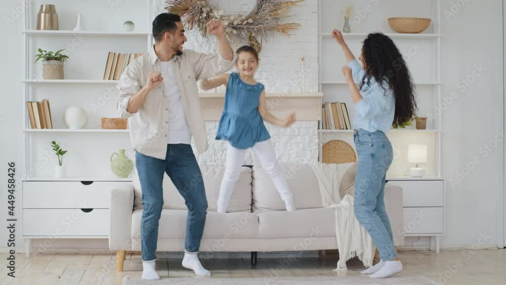 Spanish family dancing at home living room. Young parents move to music ...