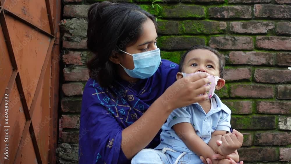 A mother tries to teach her child to wear a safety mask to prevent ...