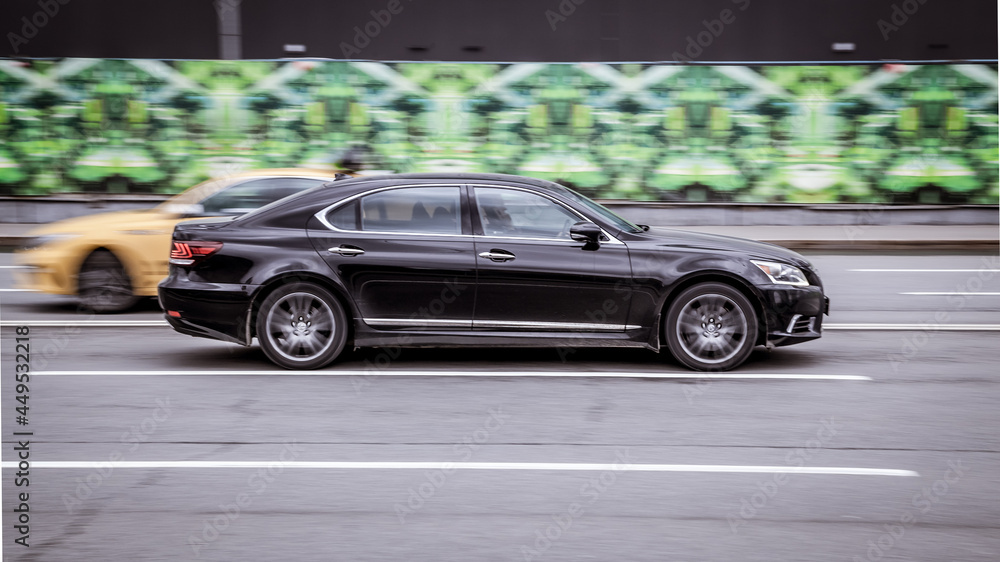 Side view of Lexus LS 460 XF40 in motion. Black Full-size luxury car driving on asphalt city ...