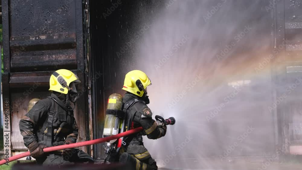 Fireman team spray water as circular around area in front of burning ...