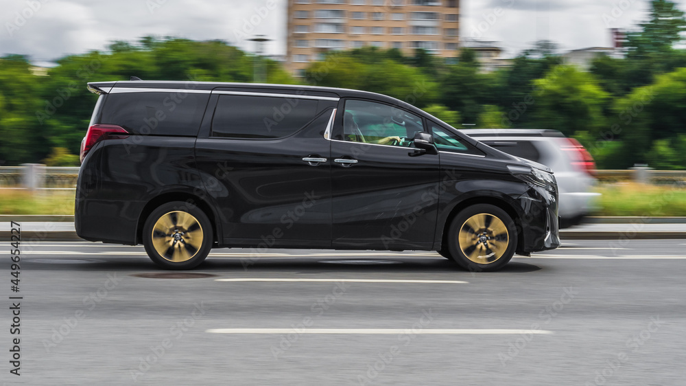 Fast moving Toyota Alphard on the city road. Black high class minivan ...