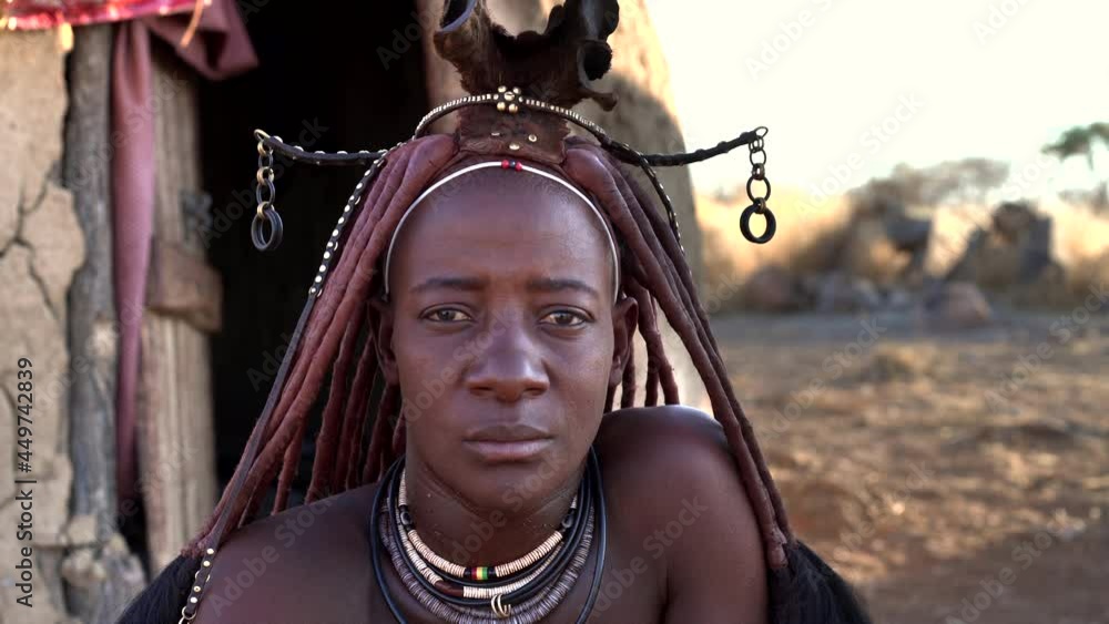 Married Himba woman looking at camera and wearing traditional jewelry ...