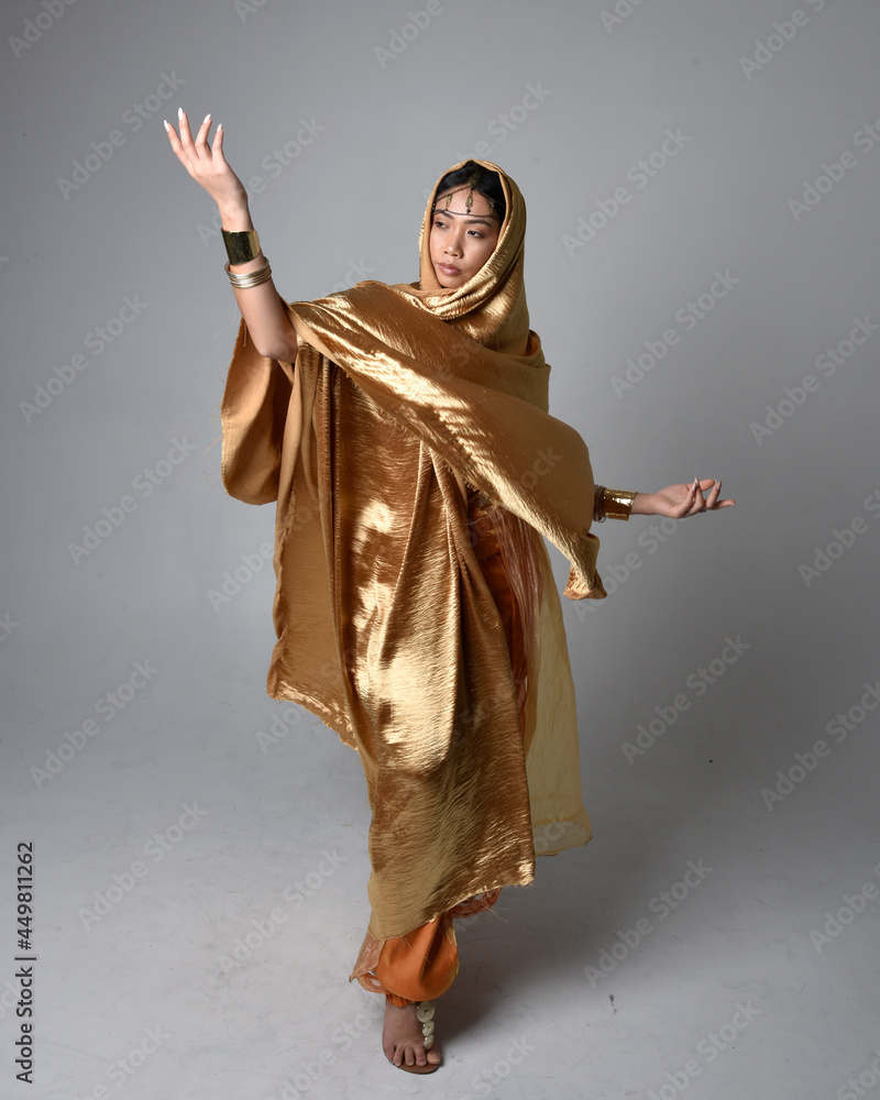 Full length portrait of pretty young asian woman wearing golden Arabian ...