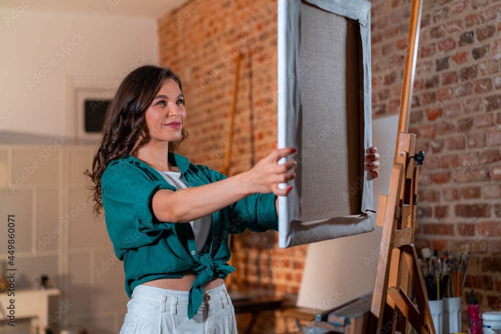 painting teacher with green eyes placing a canvas on the easel to start ...