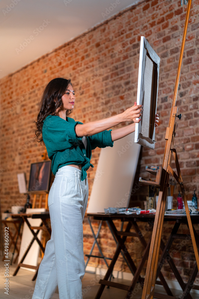 painting teacher with green eyes placing a canvas on the easel to start ...