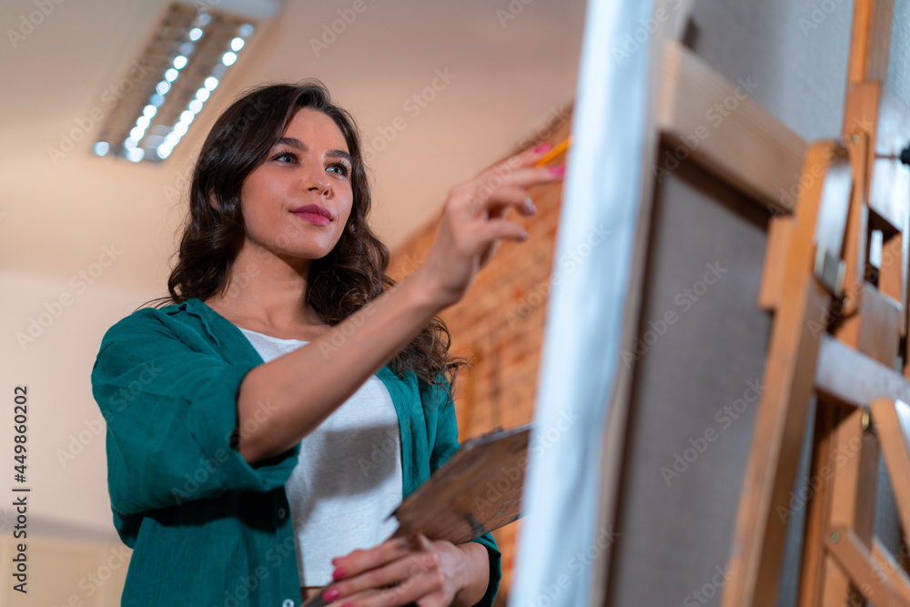 painting teacher with green eyes drawing on canvas with smile and using ...
