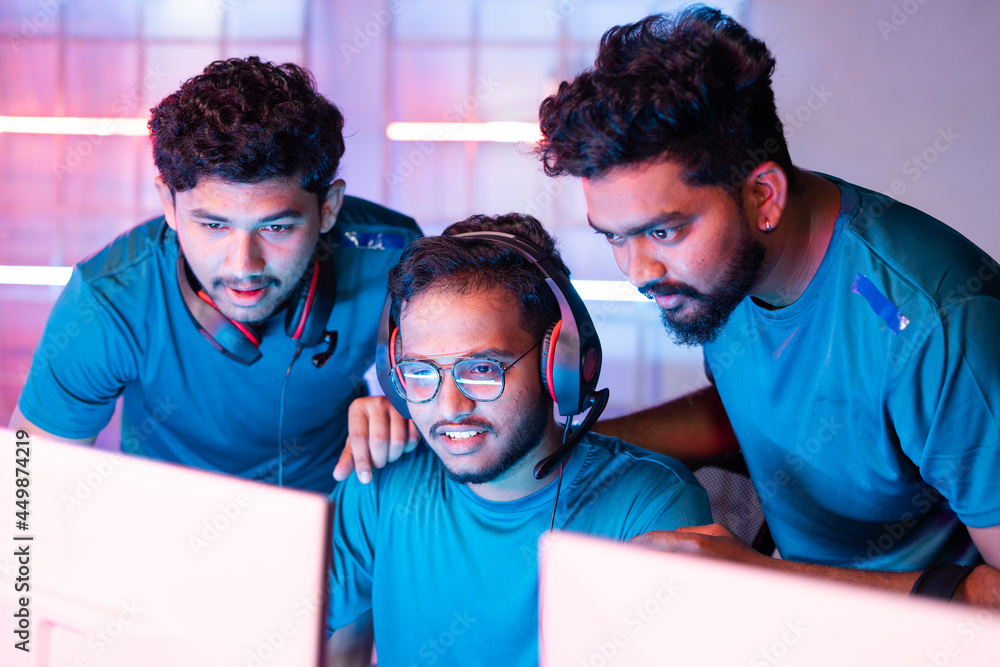 Team of gamers discussing about game play by looking into monitor at ...